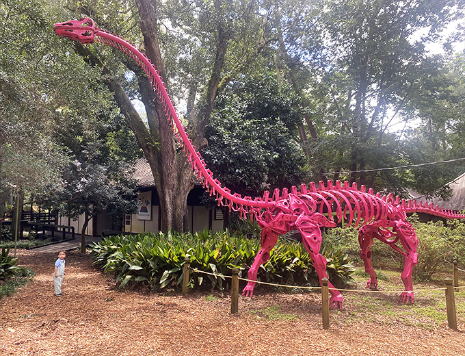 Children stand mesmerized by this towering pink apatosaurus, its long neck creating the perfect prehistoric selfie opportunity.