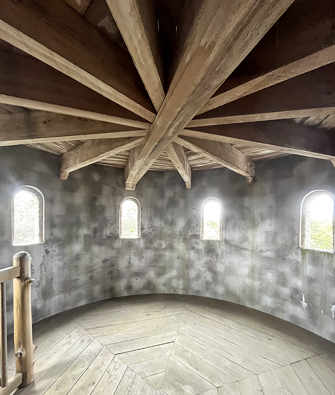 Sunlight filters through narrow openings beneath a spectacular wooden ceiling that radiates with geometric precision.