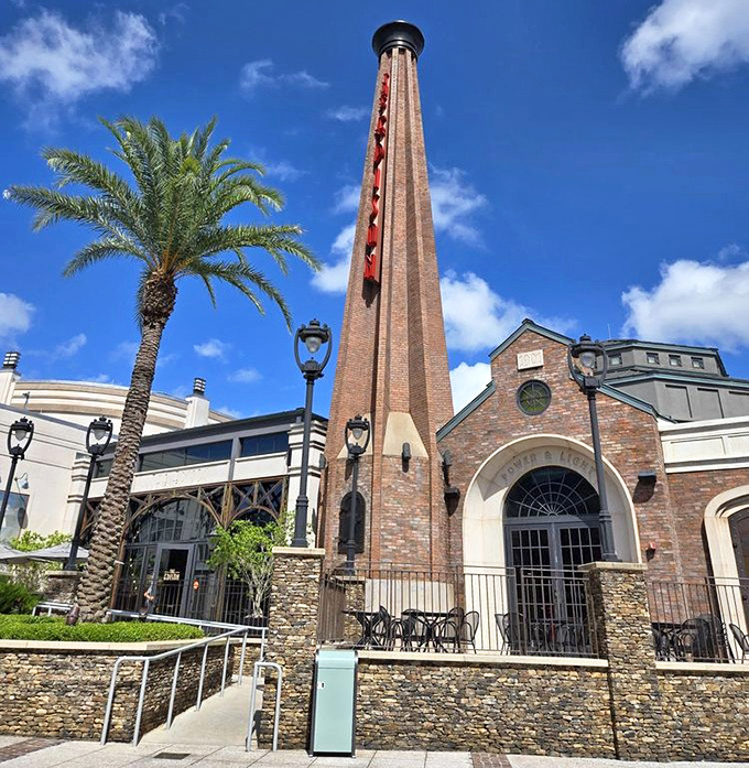 The Edison's industrial-chic exterior features a towering brick smokestack that dominates the skyline. This 1920s power plant conversion stands out among Disney Springs' restaurants.