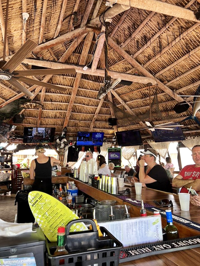 The bar area buzzes with conversation as bartenders craft tropical concoctions under the watchful gaze of ceiling fans and tiki gods.