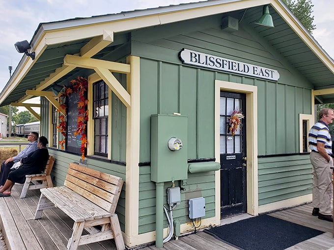 The charming Blissfield East station stands ready for departure, its vintage green siding and wooden benches setting the stage for time travel.