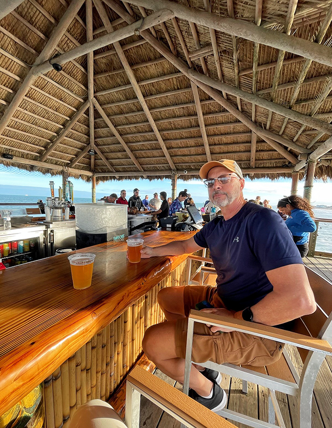 Beneath the thatched roof, patrons enjoy the simple luxury of cold beer and endless horizon &ndash; a reminder that sometimes the best entertainment is just being present.