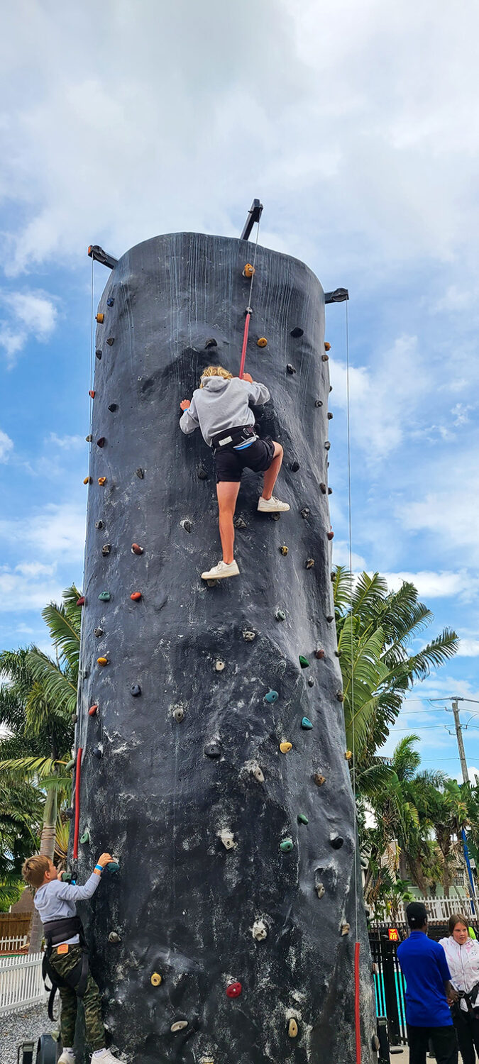 A determined climber scales the rock wall, proving that Andretti offers vertical thrills alongside its horizontal racing adventures.