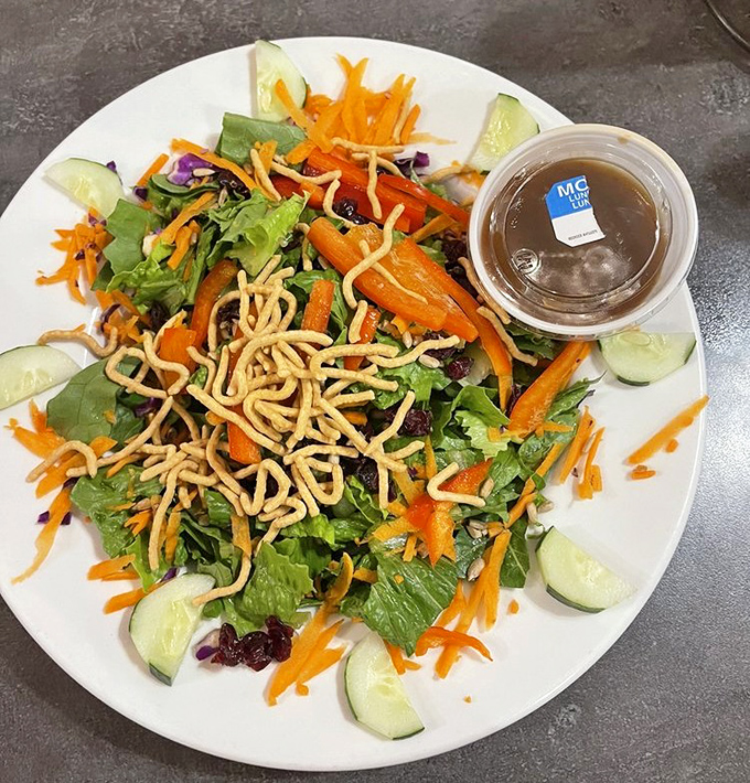 A vibrant garden party topped with crunchy noodles and surrounded by cucumber slices&mdash;proof that eating greens can be both virtuous and delicious.