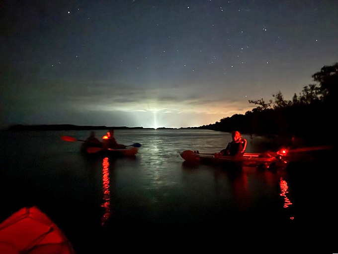 Under a canopy of stars, red safety lights create an otherworldly scene as kayakers wait for the waters to reveal their secret.