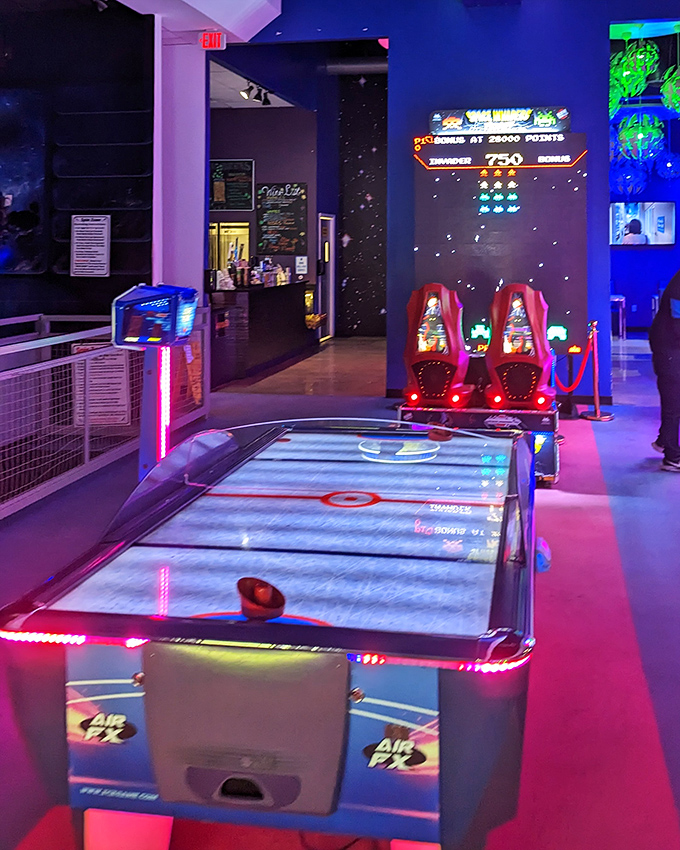 Air hockey tables glow with competitive spirit, where friendships are temporarily suspended for the glory of sliding puck supremacy.