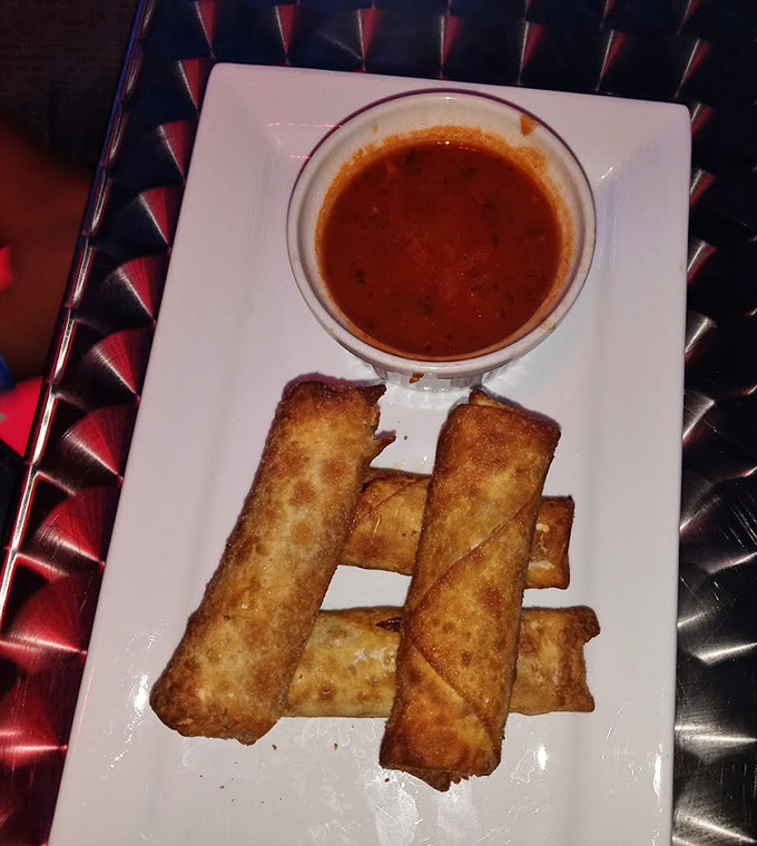 Crispy egg rolls with dipping sauce offer a warm, satisfying bite between sips of icy cocktails &ndash; comfort food meets cool environment.