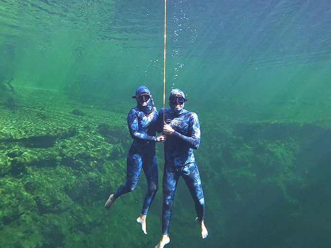 Freedivers suspended in the emerald depths, where the weightlessness of water creates a meditation in motion.