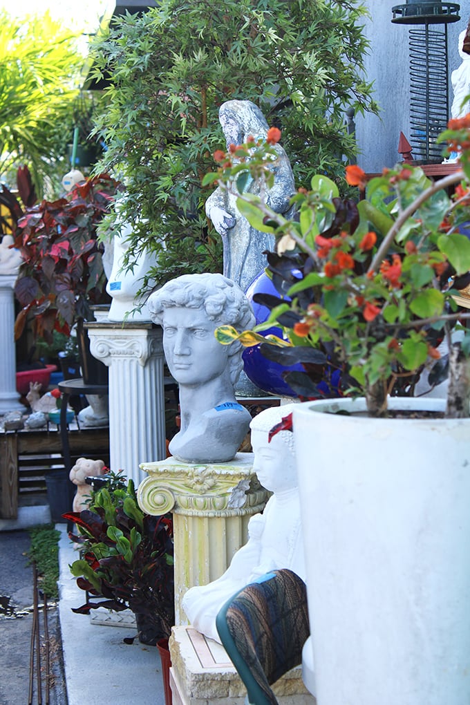 Classical busts and garden statuary create an outdoor gallery where stone faces silently judge your landscaping choices from their pedestals.