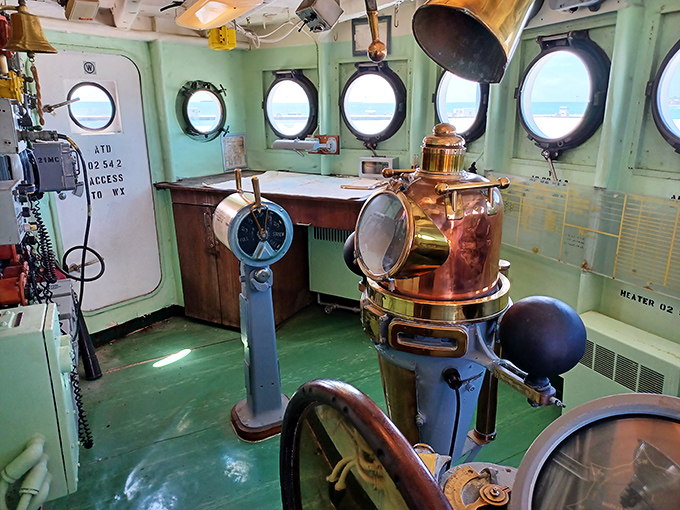 Porthole windows offer glimpses of Key West's turquoise waters while brass fixtures gleam against the mint-green bulkheads of this preserved compartment.