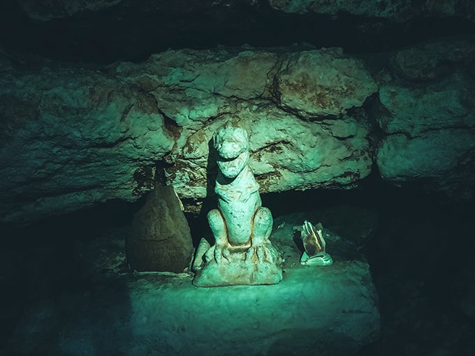 An underwater statue stands sentinel in the depths, greeting cave divers like an ancient guardian of this subterranean realm.