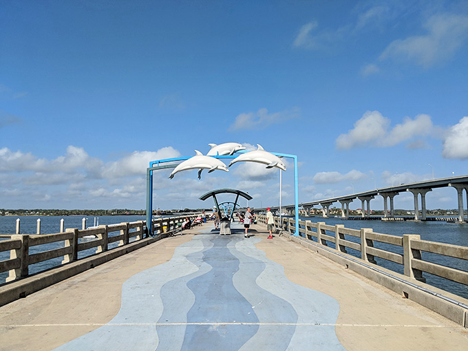 Vilano Beach Fishing Pier stretches into the Atlantic, decorated with cheerful dolphin sculptures overhead.