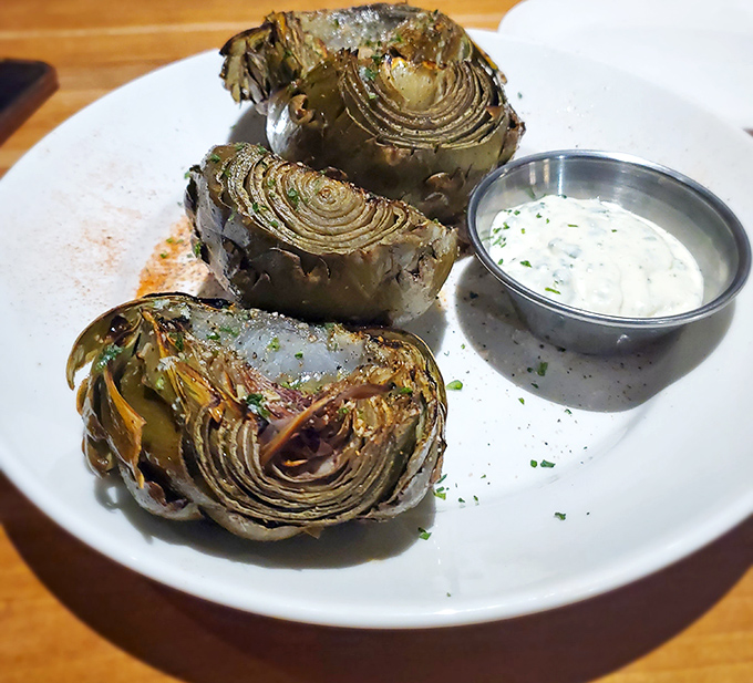 Fire-grilled artichokes &ndash; nature's most armored vegetable transformed into tender, smoky deliciousness with dipping sauce that complements without overwhelming.