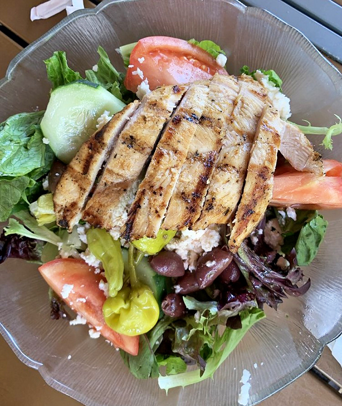 A Mediterranean vacation on a plate &ndash; grilled chicken rests atop a colorful landscape of fresh vegetables and feta.