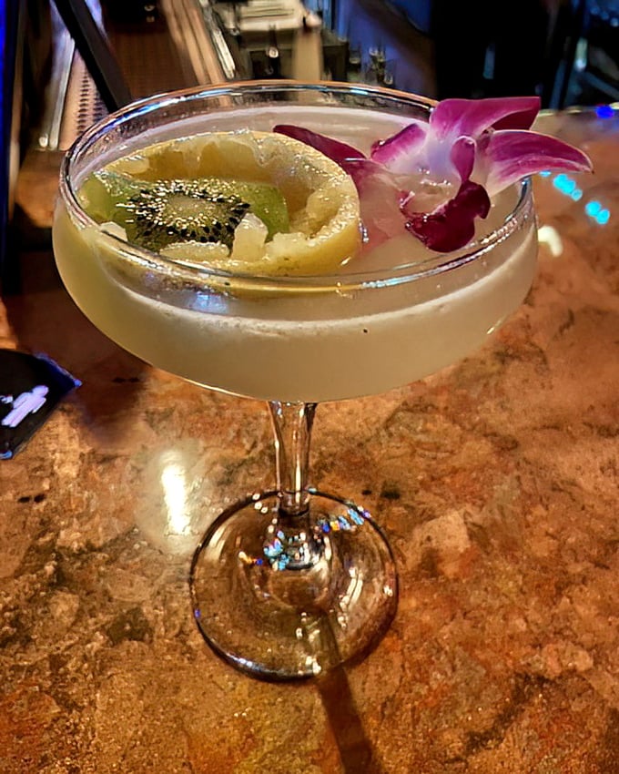 Another magical elixir from the bar's extensive "spellbook" of signature cocktails, garnished with fresh fruit and edible flowers.