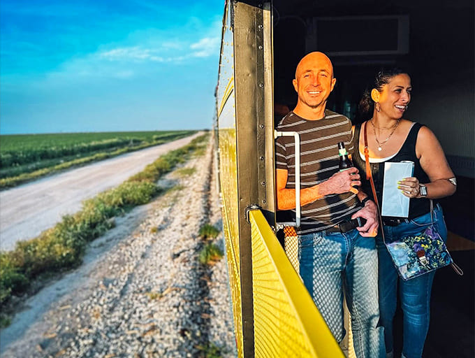 Passengers lean out to catch the breeze and the view, their faces showing the pure joy of experiencing travel the old-fashioned way.