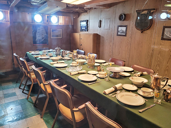 The captain's dining room exudes naval elegance with its formal place settings and wood-paneled walls &ndash; dinner is served at sea!