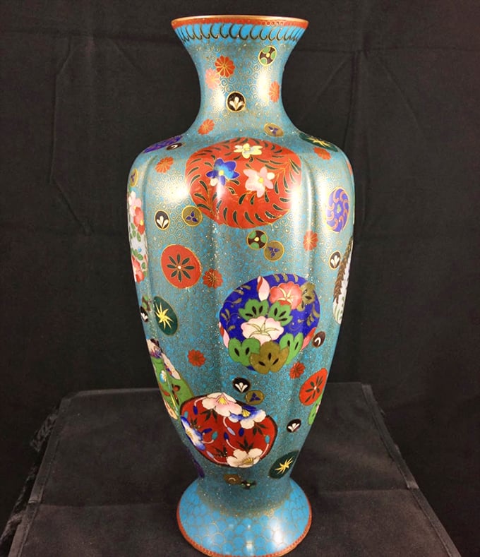 The cloisonn&eacute; vase explodes with color and craftsmanship, its intricate metalwork framing vibrant enameled designs that seem almost illuminated from within.