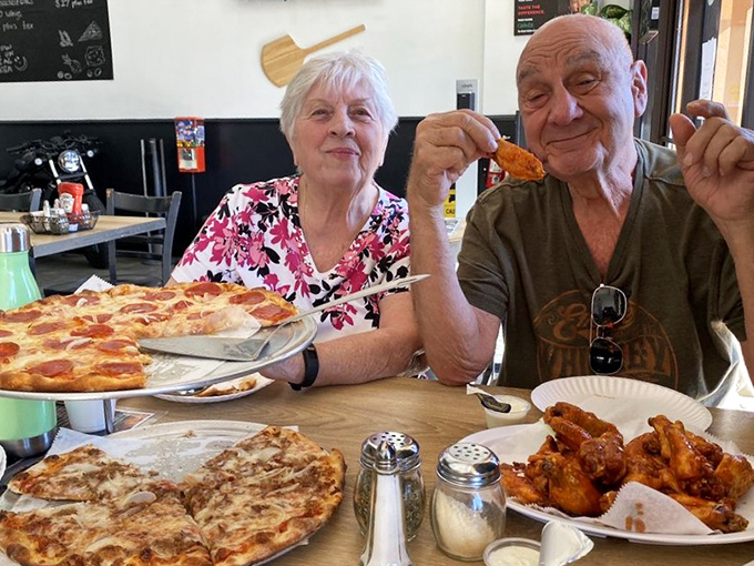 Happy customers experiencing that universal "good pizza face" &ndash; eyes closed, slight smile, momentarily forgetting they're in a public place.