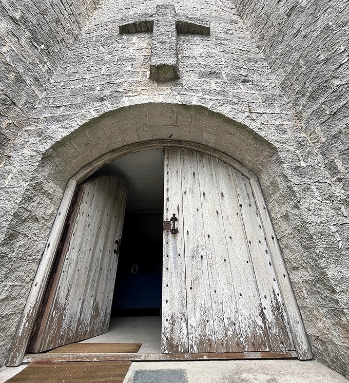 Weathered wooden doors stand partially open, revealing glimpses of the spiritual sanctuary waiting within these ancient-looking walls.