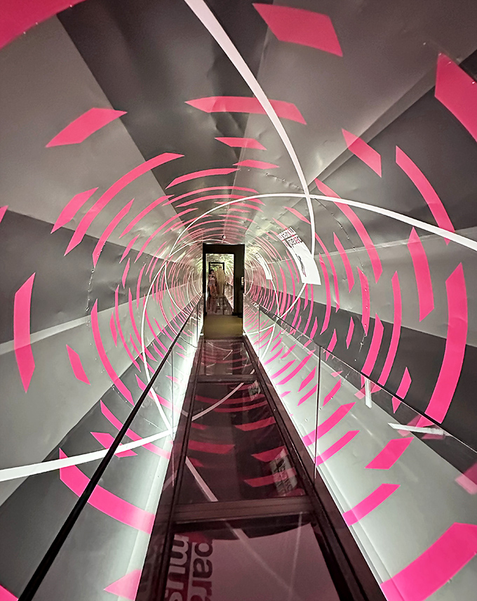 A hypnotic tunnel of pink and white lines creates a vortex effect that makes walking straight feel like an Olympic sport. Your eyes say "roller coaster" while your feet insist you're on solid ground.