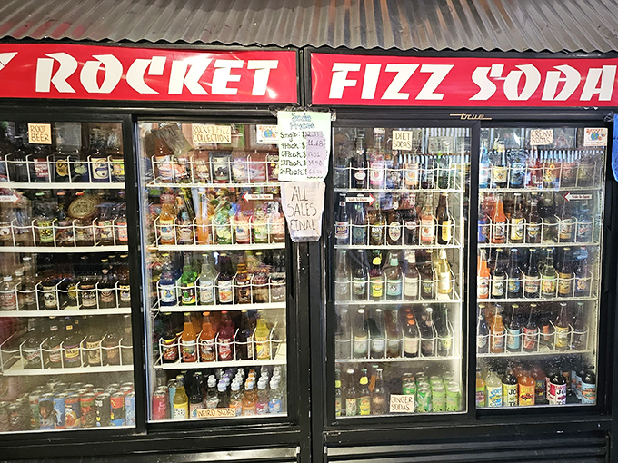 The refrigerated case glows like a treasure chest of liquid nostalgia, with sodas arranged by color creating an irresistible rainbow of fizzy possibilities.