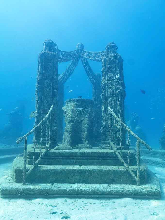 Stone columns frame a central memorial marker, creating a sacred space that feels both ancient and timeless beneath the waves.