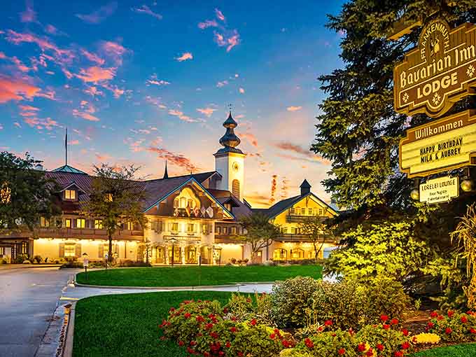 The Bavarian Inn Lodge glows at sunset, its clock tower and Alpine architecture creating a magical silhouette against Michigan's evening sky.