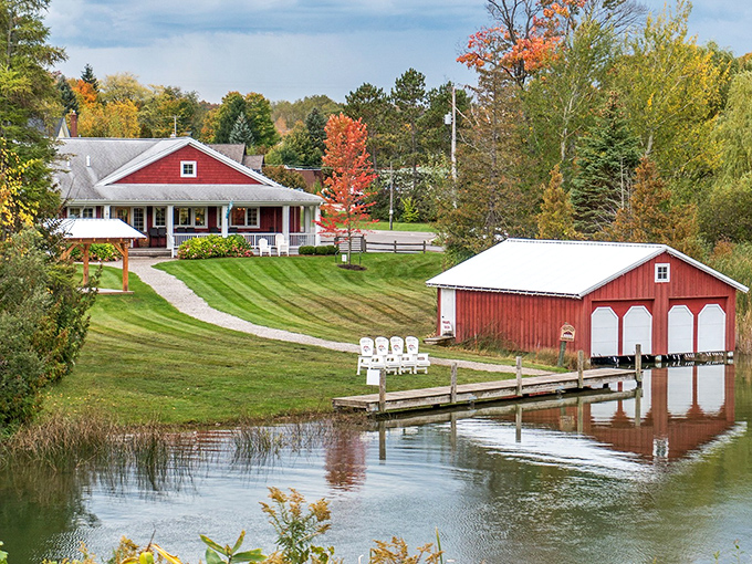 A picture-perfect Michigan scene: the iconic red buildings of Boathouse Vineyards reflect in the calm waters of Lake Leelanau, creating postcard-worthy charm.