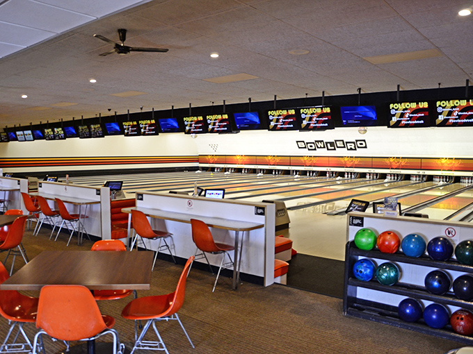 Classic lanes stretch into the distance at Bowlero, where orange chairs pop against polished wood like exclamation points of fun.