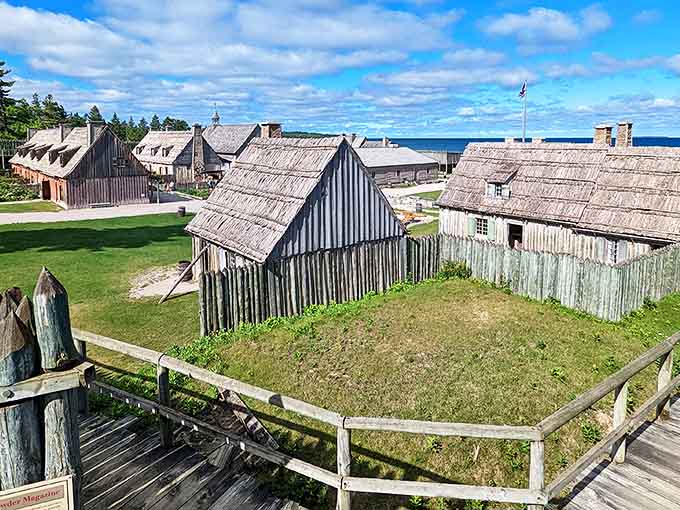 A living postcard from 1775: Colonial Michilimackinac's weathered wooden buildings stand proudly against Michigan's brilliant blue skies, history frozen in architectural amber.