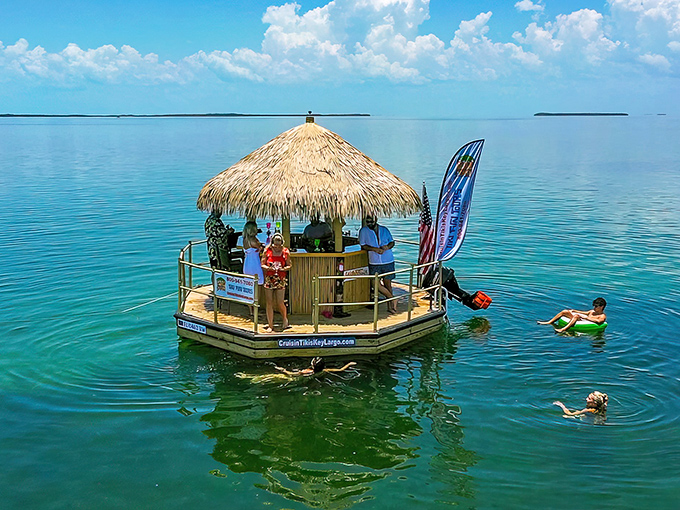 A tropical paradise afloat: Cruisin' Tikis' circular floating bar bobs gently in Key West's crystal waters, inviting swimmers to cool off nearby.
