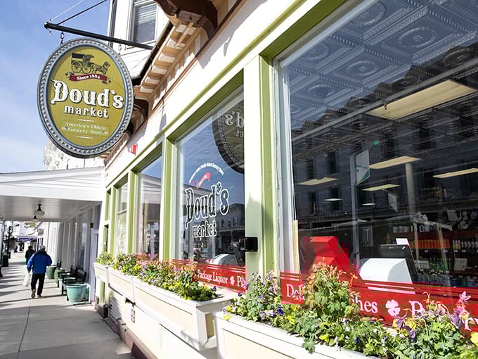 The iconic green-trimmed fa&ccedil;ade of Doud's Market welcomes visitors with vintage charm and colorful flower boxes, a Main Street landmark on car-free Mackinac Island.