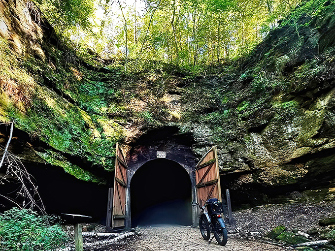 The entrance to one of Wisconsin's historic railroad tunnels stands like a portal to adventure, wooden doors beckoning cyclists forward.
