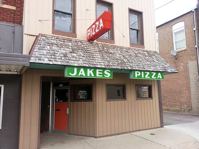 The unassuming exterior of Jake's Pizza beckons with its classic signage &ndash; proof that the best treasures often hide in plain sight.