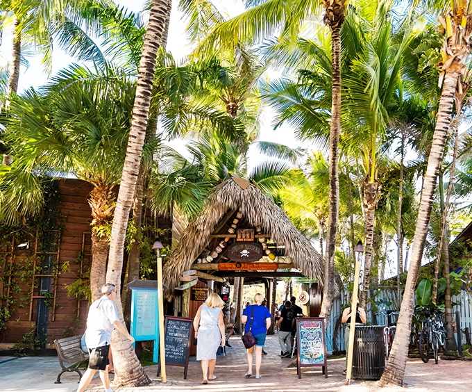 A tropical gateway beckons beneath swaying palms, where the Square Grouper's thatched entrance promises escape from the ordinary world.