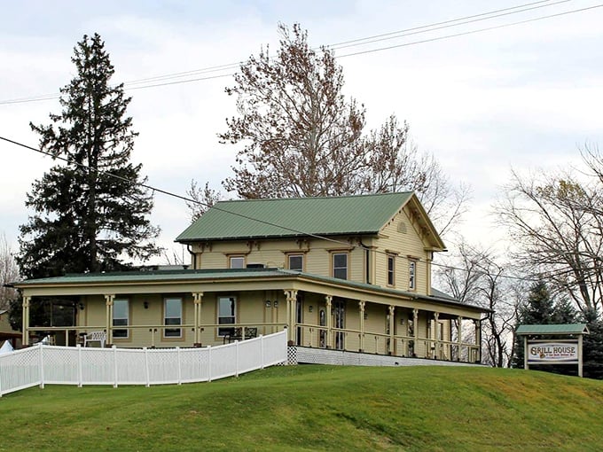 The Grill House's charming yellow farmhouse with green roof sits proudly on a hill, welcoming hungry travelers like a beacon of culinary comfort.