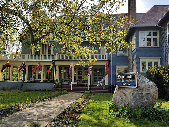 Stately blue Queen Anne mansion with international flags waving a cheerful "hello!" – Downton Abbey meets Midwest hospitality.