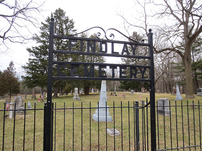 The wrought iron entrance to Findlay Cemetery stands like a portal between worlds, inviting the brave while warning the wary.