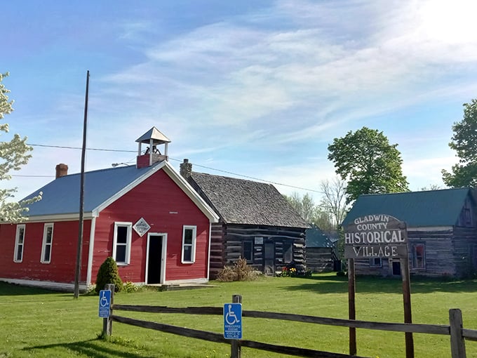 The iconic red schoolhouse and weathered log cabin create a striking visual timeline of rural Michigan life at Gladwin County Historical Village.