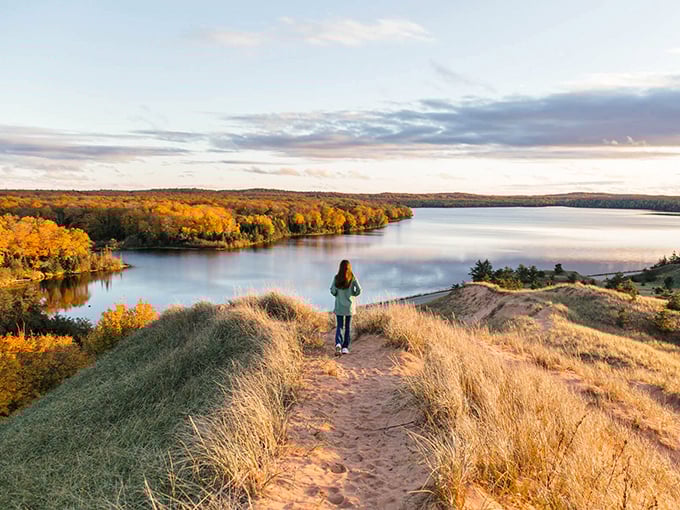 Autumn's golden touch transforms Grand Sable Lake into a painter's dream, where forest meets water in perfect harmony.