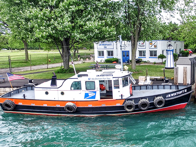 The J.W. Westcott II stands ready for duty, its white and orange-red hull gleaming against the Detroit River's blue waters.