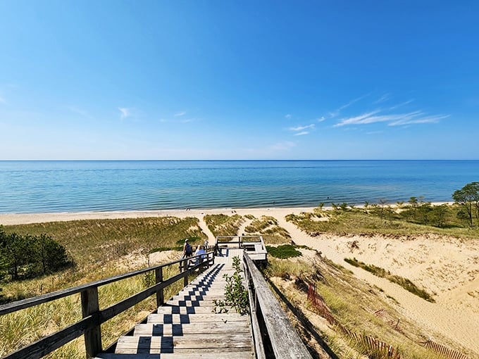 A wooden stairway descends to paradise, where Lake Michigan's endless blue horizon meets pristine golden sand.