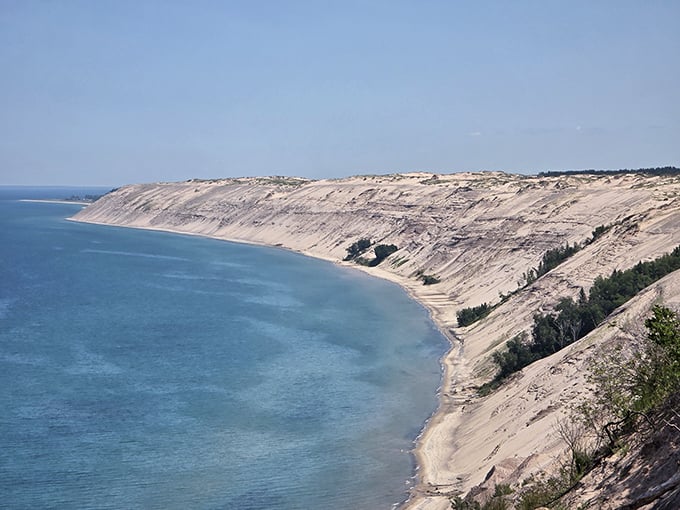 Nature's grand balcony: towering sand cliffs meet endless blue waters, creating Michigan's most dramatic coastal vista.
