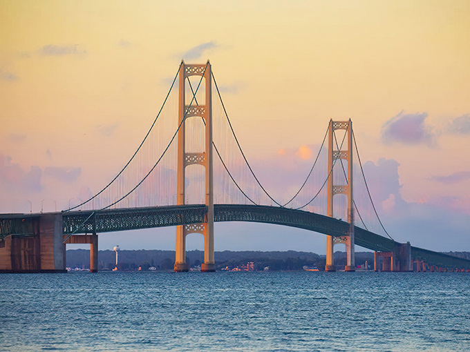 The Mighty Mac glows golden at sunset, its 26,372-foot span connecting Michigan's two peninsulas across the swirling Straits.