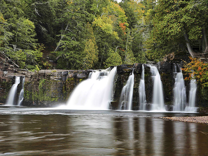 Manabezho Falls commands attention as it cascades over ancient volcanic rock, nature's own theatrical production in Michigan's wilderness.