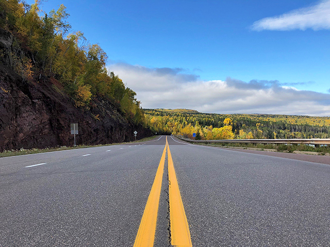 The North Shore Scenic Drive unfurls like nature's red carpet, golden autumn trees standing at attention while Lake Superior whispers promises of adventure ahead.