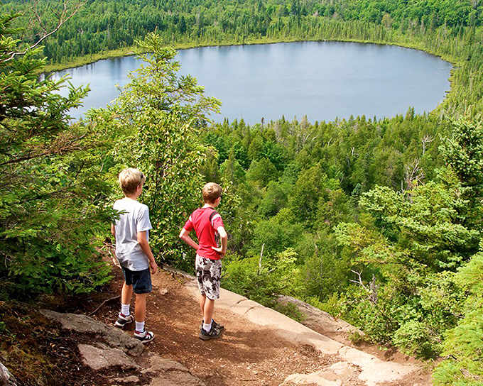 Oberg Mountain Trail: Two young adventurers gaze upon nature's infinity pool – a perfect circle of blue nestled in an endless green carpet.