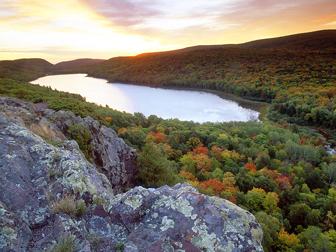 Sunset paints the Porcupine Mountains in golden hues, with Lake of the Clouds nestled between forest-covered ridges like nature's perfect infinity pool.