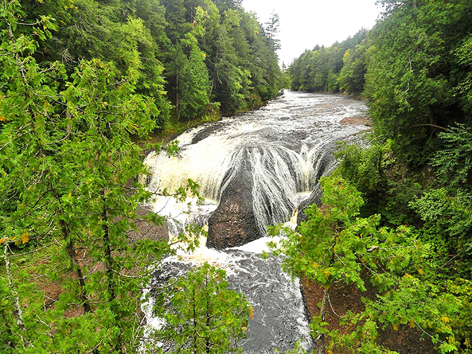 Nature's perfect cascade &ndash; Potawatomi Falls tumbles gracefully over ancient red bedrock, surrounded by Michigan's lush northern forest.
